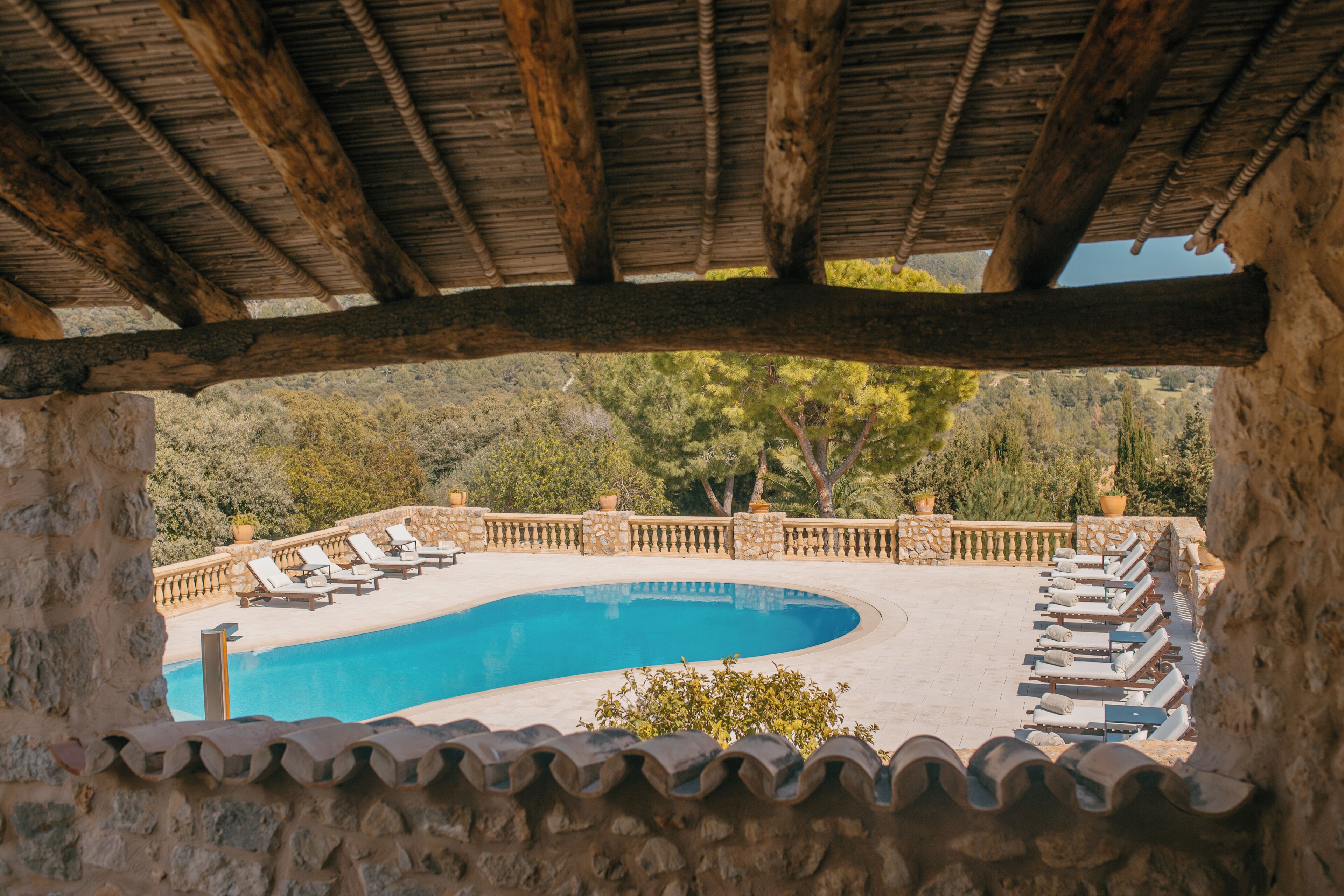 Uma área de piscina com espreguiçadeiras e um muro de pedra.