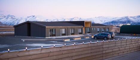 Um edifício moderno com telhado plano e grandes janelas, localizado em uma paisagem nevada com montanhas ao fundo.