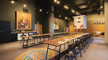 Uma sala de conferência com uma mesa comprida, cadeiras, um tapete colorido e obras de arte nas paredes.