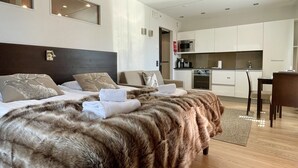 Quarto de hotel moderno com uma cama grande, uma kitchenette pequena e uma área de refeições.