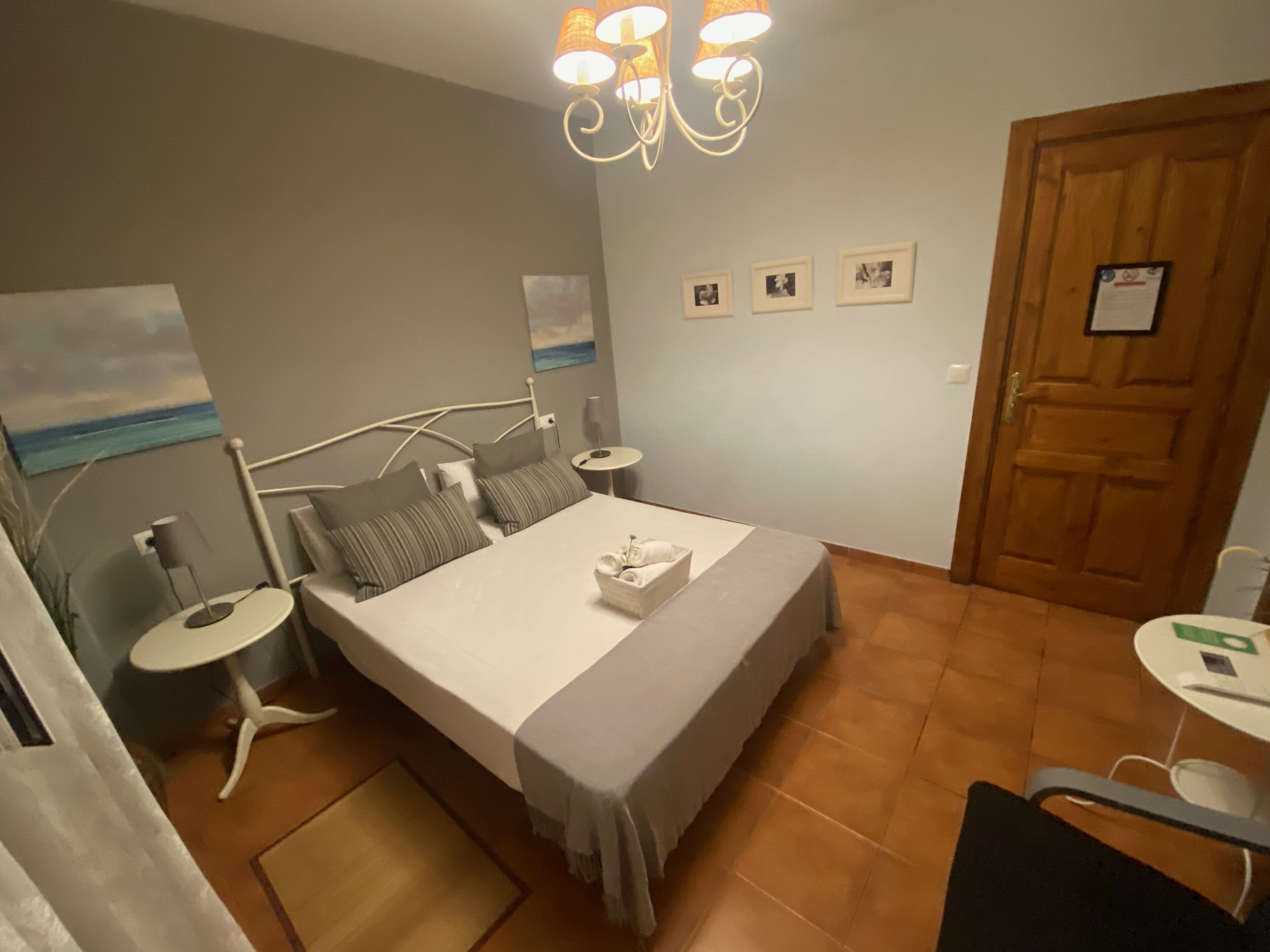 Quarto com cama, mesas de cabeceira, luminária, quadro e porta.