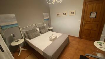 Quarto com cama, mesas de cabeceira, luminária, quadro e porta.