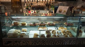 Vitrine de pastelaria com diversos pastéis e sanduíches.