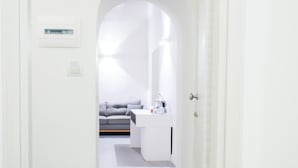 Corredor que dá para uma sala de estar com sofá e mesa de centro branca.