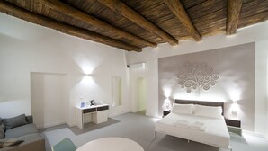 Quarto moderno com cama, mesas de cabeceira, escrivaninha e sofá.