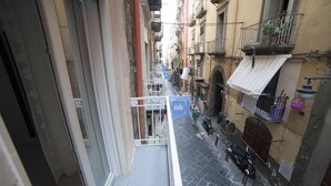Uma rua estreita com edifícios em ambos os lados, uma placa azul e motocicletas estacionadas.