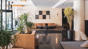 Um lobby moderno com um sofá, mesa de centro e plantas em vasos.