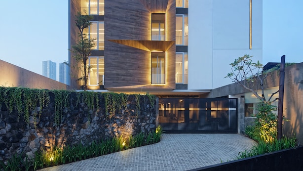 Um edifício moderno com fachada de pedra, entrada pavimentada e interior bem iluminado.