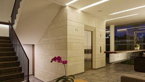 Um interior moderno com escadaria, balcão de recepção e uma orquídea em vaso.