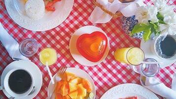 Uma mesa posta com pratos de comida, incluindo ovos, frutas e pão, sobre uma toalha quadriculada vermelha e branca.
