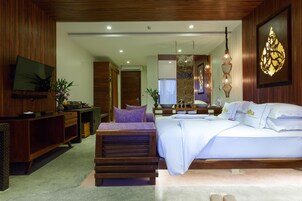 Quarto moderno com cabeceira de madeira, cama grande com roupa de cama branca, TV em móvel de madeira e um objeto decorativo na parede.