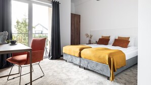 Quarto de hotel moderno com uma cama grande, uma mesa de jantar e vista para o exterior.