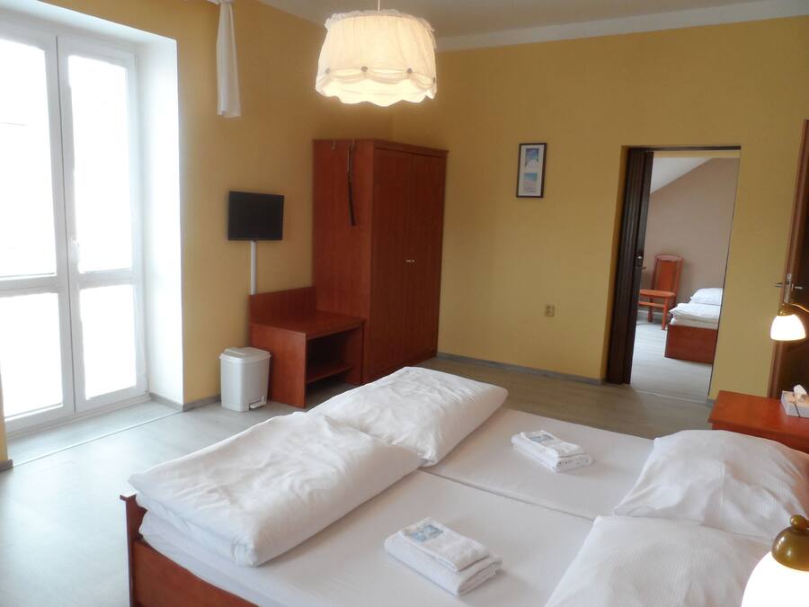 Quarto de hotel com cama, guarda-roupa, escrivaninha e cadeira.