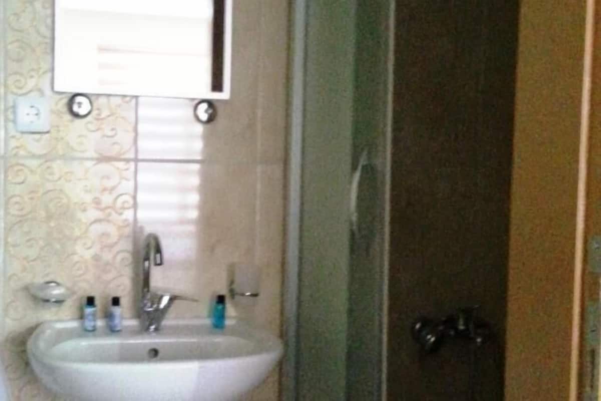 Casa de banho com lavatório, espelho e artigos de higiene pessoal.