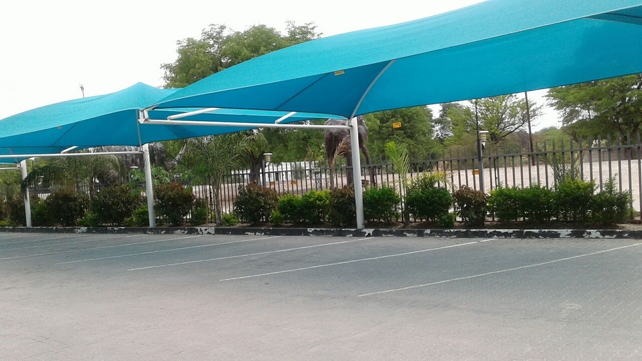 Um estacionamento com toldos azuis que oferecem sombra.