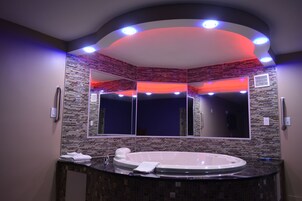 Uma casa de banho moderna com um espelho grande, uma banheira embutida e um lavatório com um porta-toalhas.