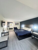 Quarto moderno com cama, mesas de cabeceira, escrivaninha e uma cadeira.