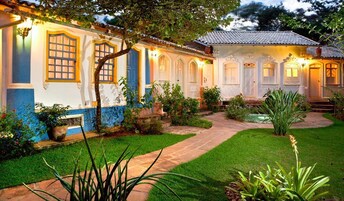 Uma casa tradicional com telhado de telhas, um caminho de pedras e um jardim bem cuidado.