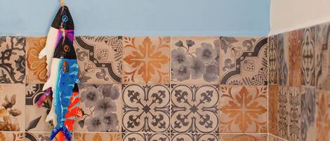 Uma cozinha com pia, um objeto decorativo pendurado e azulejos estampados.