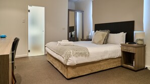 Quarto bem arrumado com uma cama grande, mesas de cabeceira, escrivaninha e ventilador de teto.