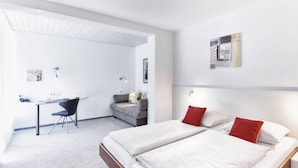 Quarto de hotel com cama, escrivaninha e sofá.