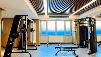 Uma academia com equipamentos de exercício, janelas amplas e teto de madeira.