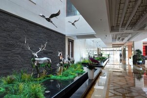 Um lobby moderno com parede preta, esculturas de chifres de veado e piso refletivo.