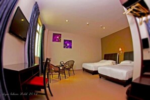 Quarto de hotel com duas camas, uma escrivaninha, uma cadeira e uma televisão.