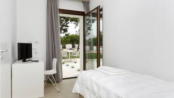 Quarto com cama, escrivaninha, cadeira e televisão.