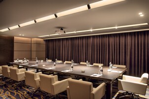 Uma sala de conferências com uma mesa comprida, cadeiras e um projetor.