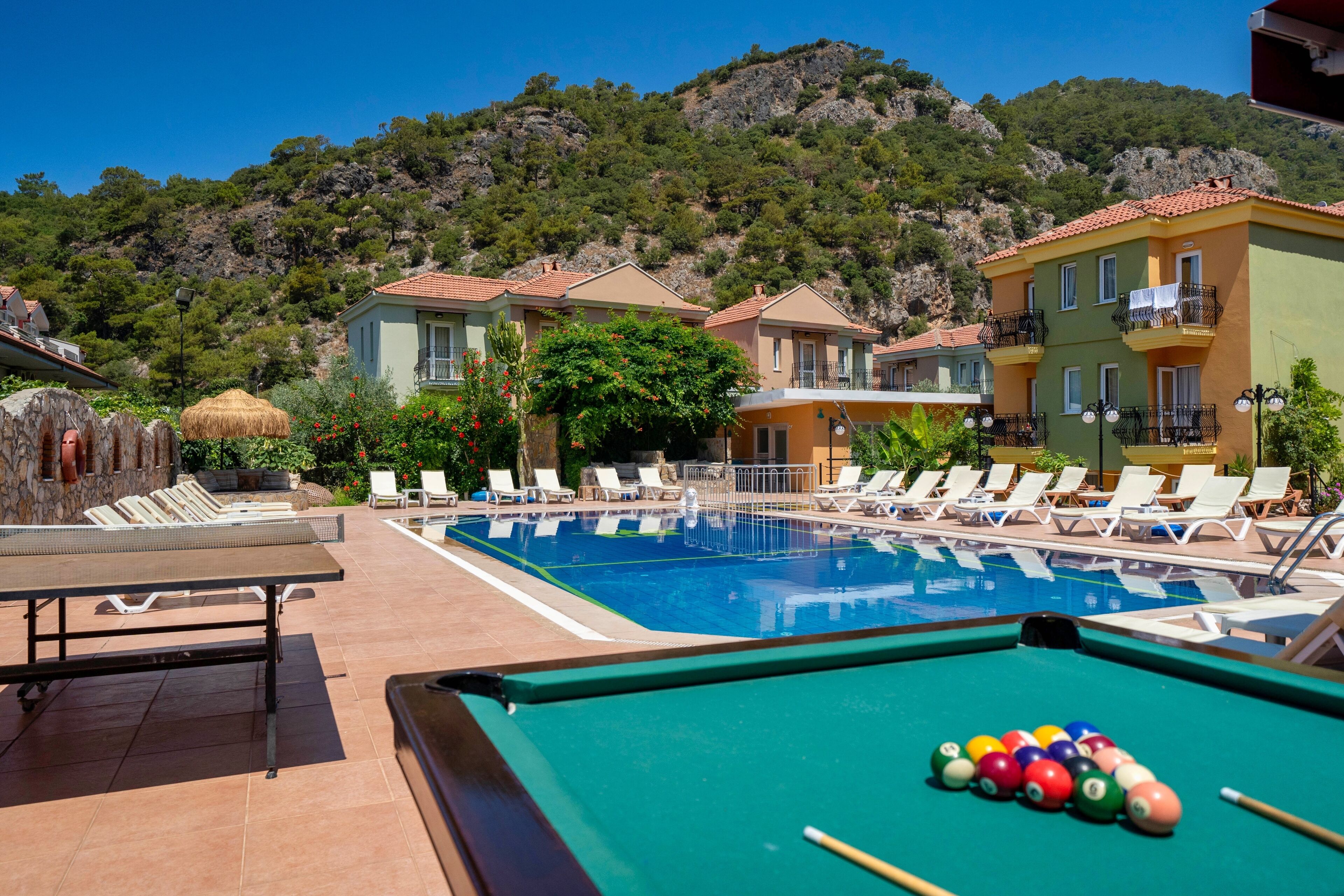 Uma área de piscina com espreguiçadeiras e mesa de bilhar.