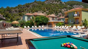 Uma área de piscina com espreguiçadeiras e mesa de bilhar.