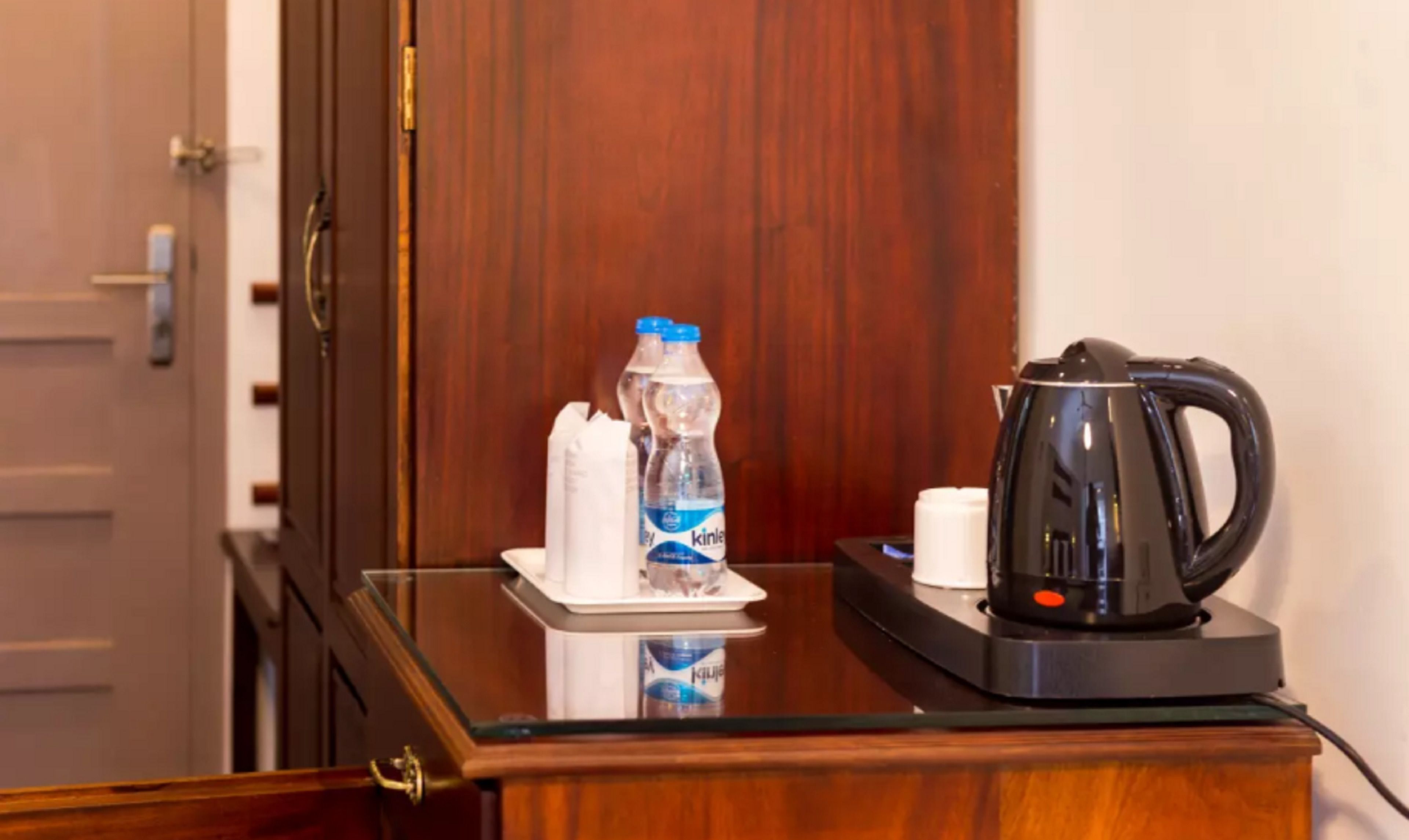 Minibar com uma garrafa de água, caixa de lenços e máquina de café.