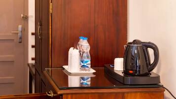 Minibar com uma garrafa de água, caixa de lenços e máquina de café.