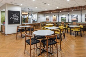 Um restaurante com mesas e cadeiras redondas, um balcão e obras de arte nas paredes.