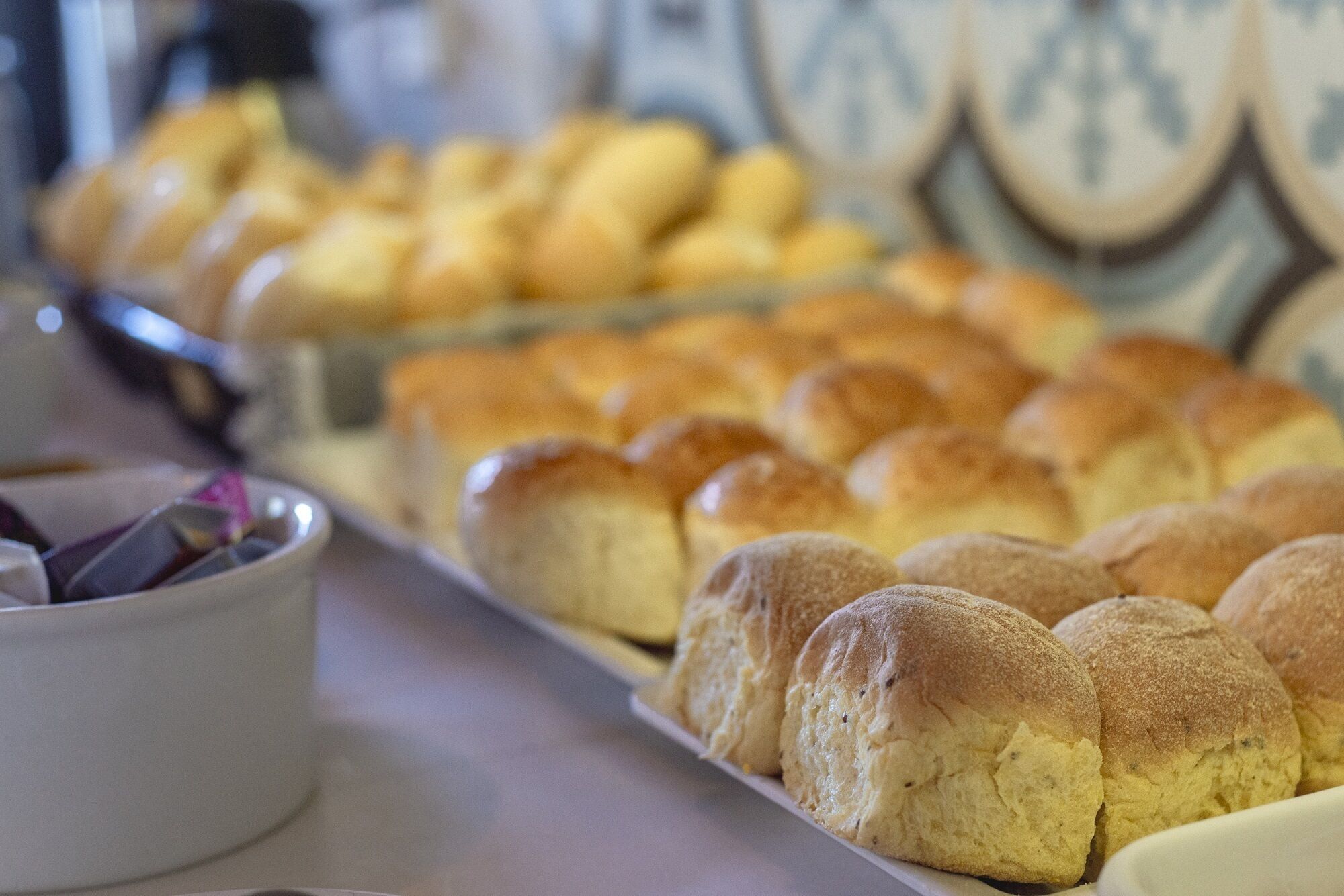 Uma mesa de buffet com diversos produtos de panificação, incluindo pães e doces.