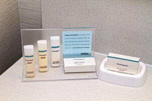 Exposição de produtos Neutrogena, incluindo shampoo, loção corporal e sabonete de banho, com um aviso oferecendo reposições gratuitas para itens esquecidos.