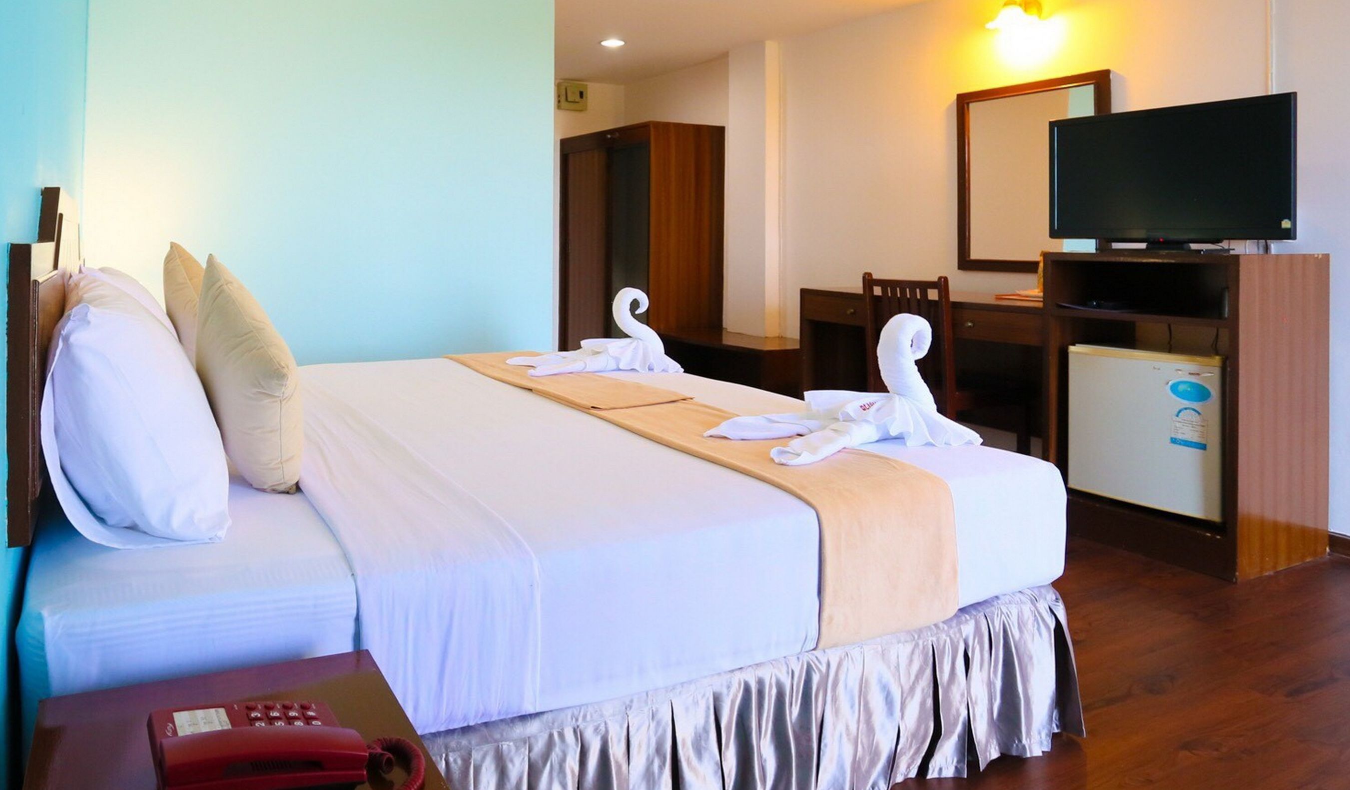Quarto de hotel com cama, escrivaninha, televisão e minibar.