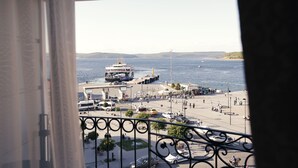 Vista de uma varanda sobre um porto, com um ferry, uma passarela para pedestres e uma área de estacionamento.
