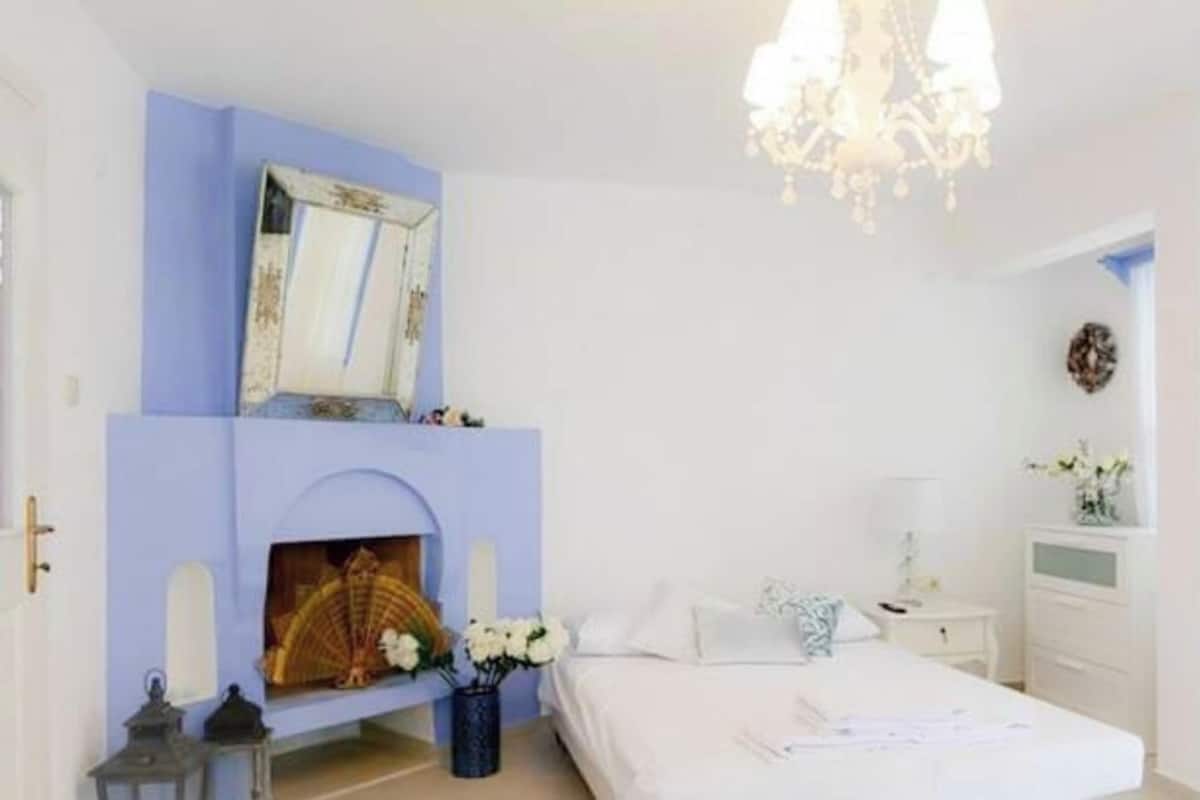 Um quarto com lareira, uma cama, uma mesa de cabeceira e um aparador.