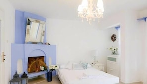 Um quarto com lareira, cama, mesa de cabeceira e cômoda.