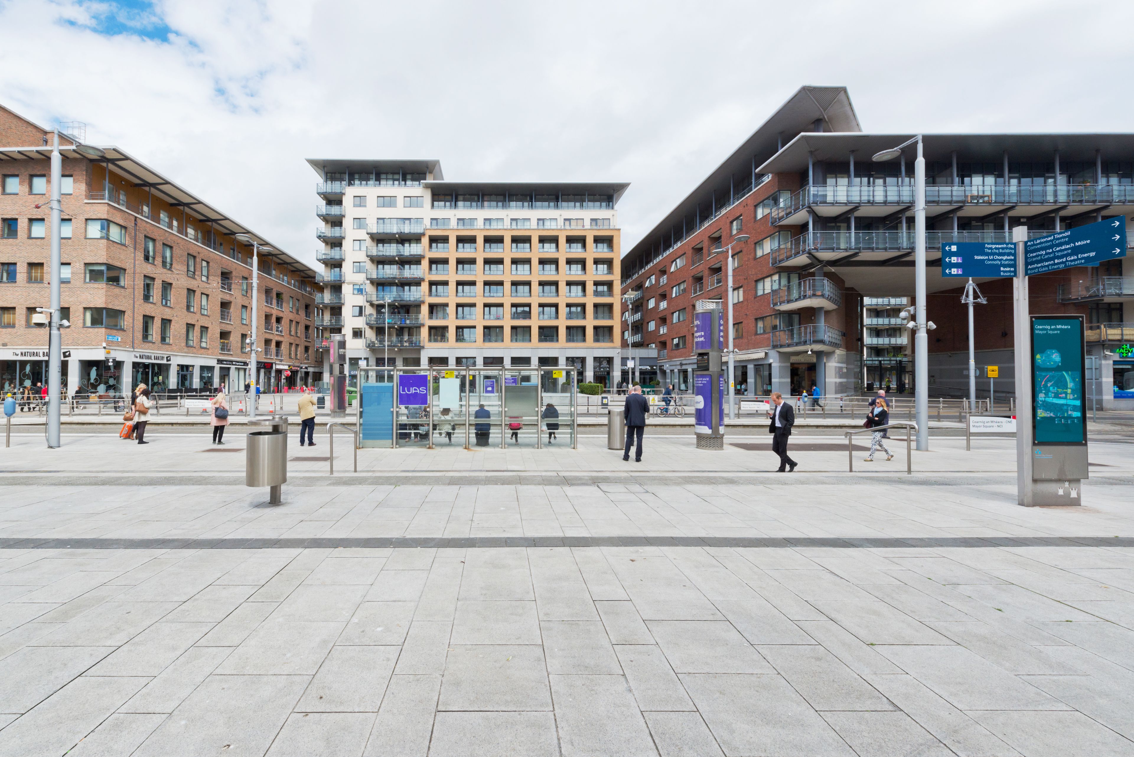 Uma praça urbana moderna com um amplo espaço aberto, rodeada por edifícios altos com varandas.