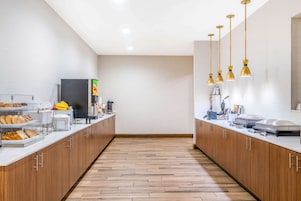 Uma cozinha moderna com bancada comprida, armários de madeira e iluminação pendente.