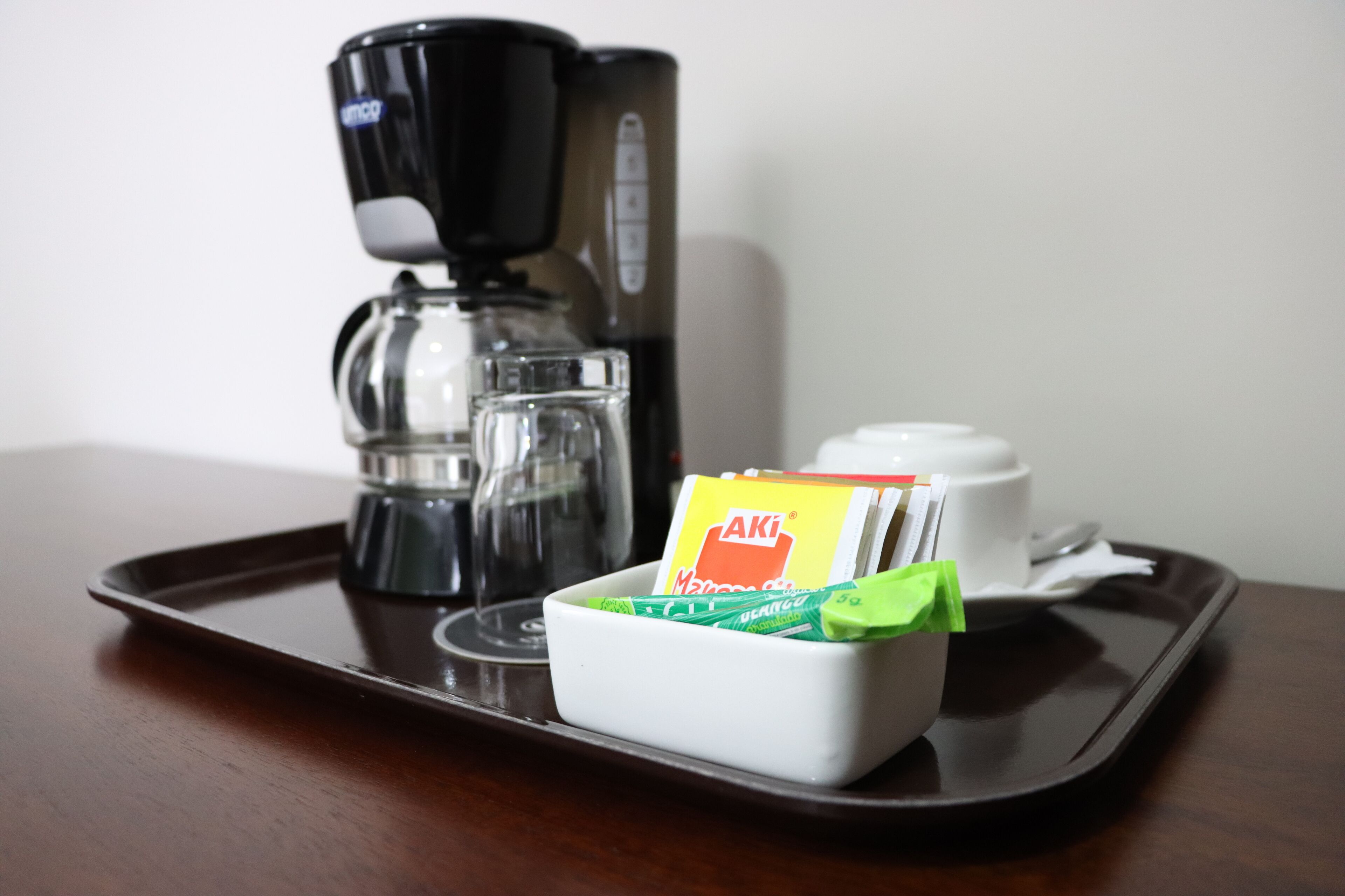 Uma bandeja com cafeteira, um copo, uma caixa de chá e uma xícara.