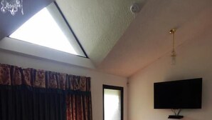 Quarto com cama, televisão e porta de correr para uma varanda.