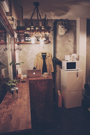 Uma cozinha compacta com uma mesa de madeira, um laptop, um micro-ondas e um lustre.
