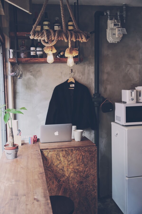Uma cozinha com bancada de madeira, um laptop, uma caneca branca e uma planta pendurada.
