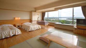 Quarto de hotel com duas camas, televisão, mesa e vista para a paisagem urbana.