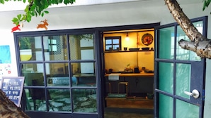 Restaurante com entrada por porta de vidro, área de cozinha visível e um letreiro na frente.