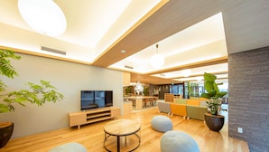 Uma sala de estar moderna com televisão, mobiliário de madeira e uma grande planta.